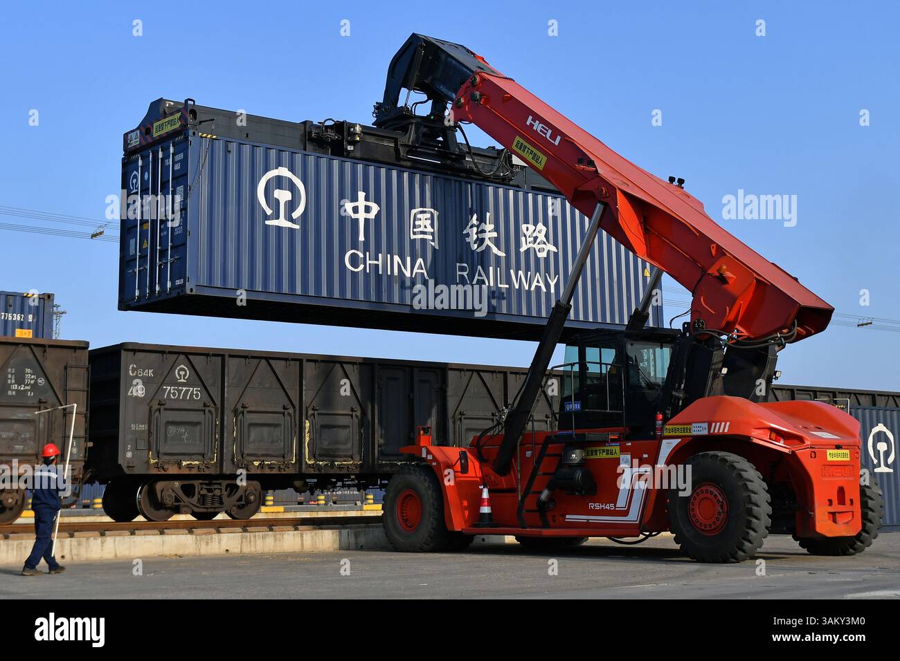 A railway container train is loaded into containers at a logistics park ...