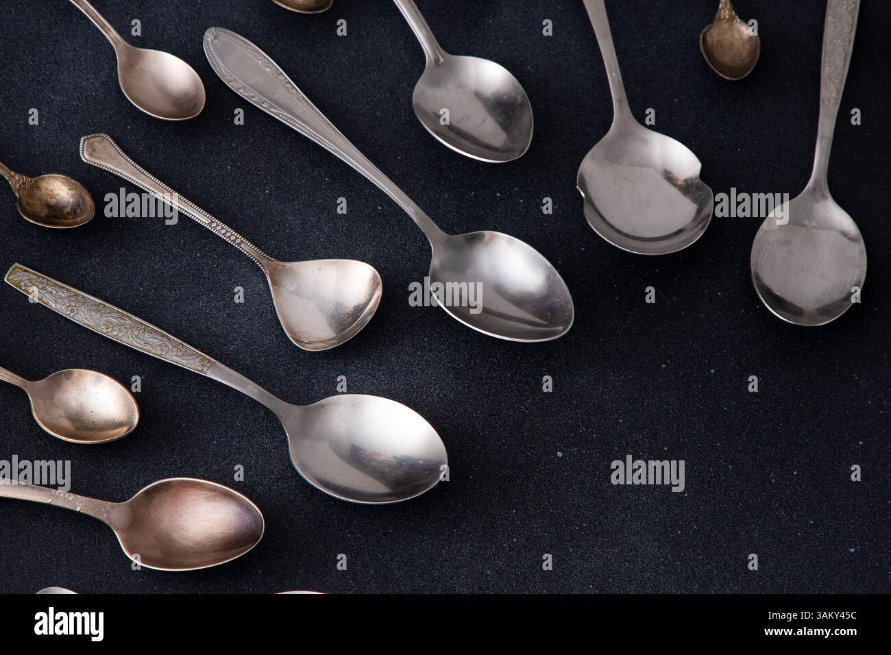 Set of different spoons. Silver cutlery on a black background. Spoon on ...