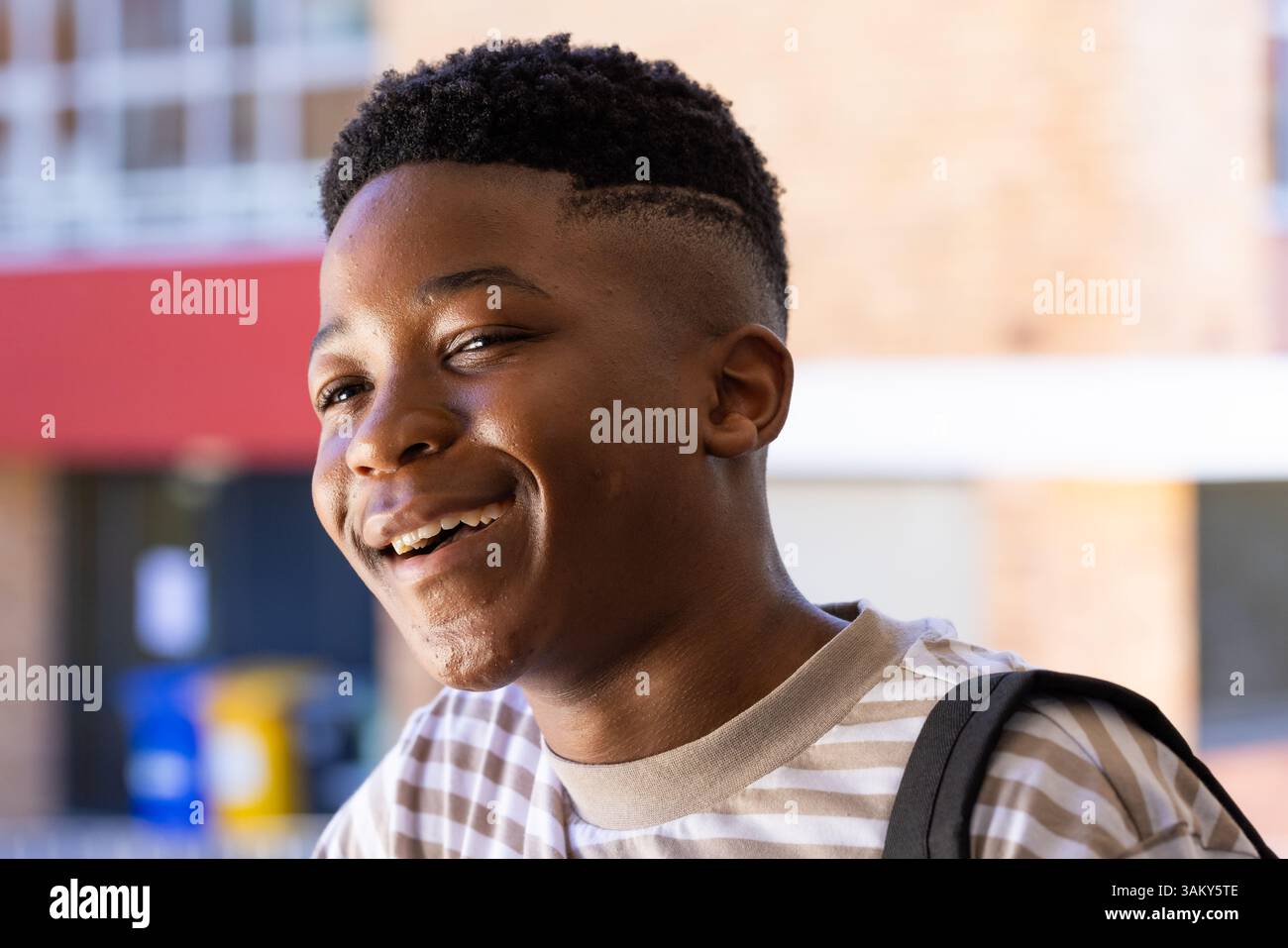 Smiling student with backpack enjoying time outside school building ...