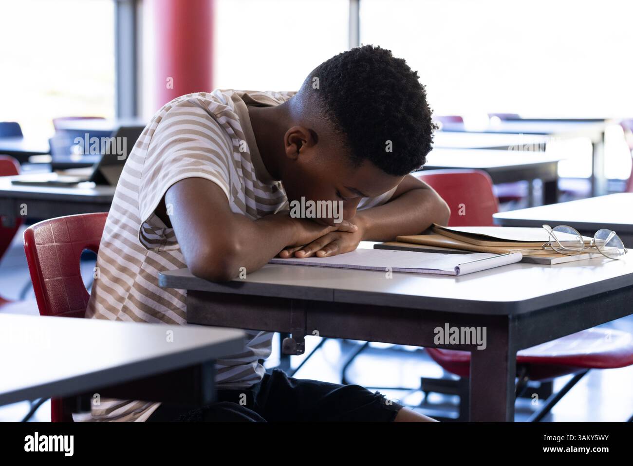 Sleeping on desk, student in school classroom with books and glasses ...