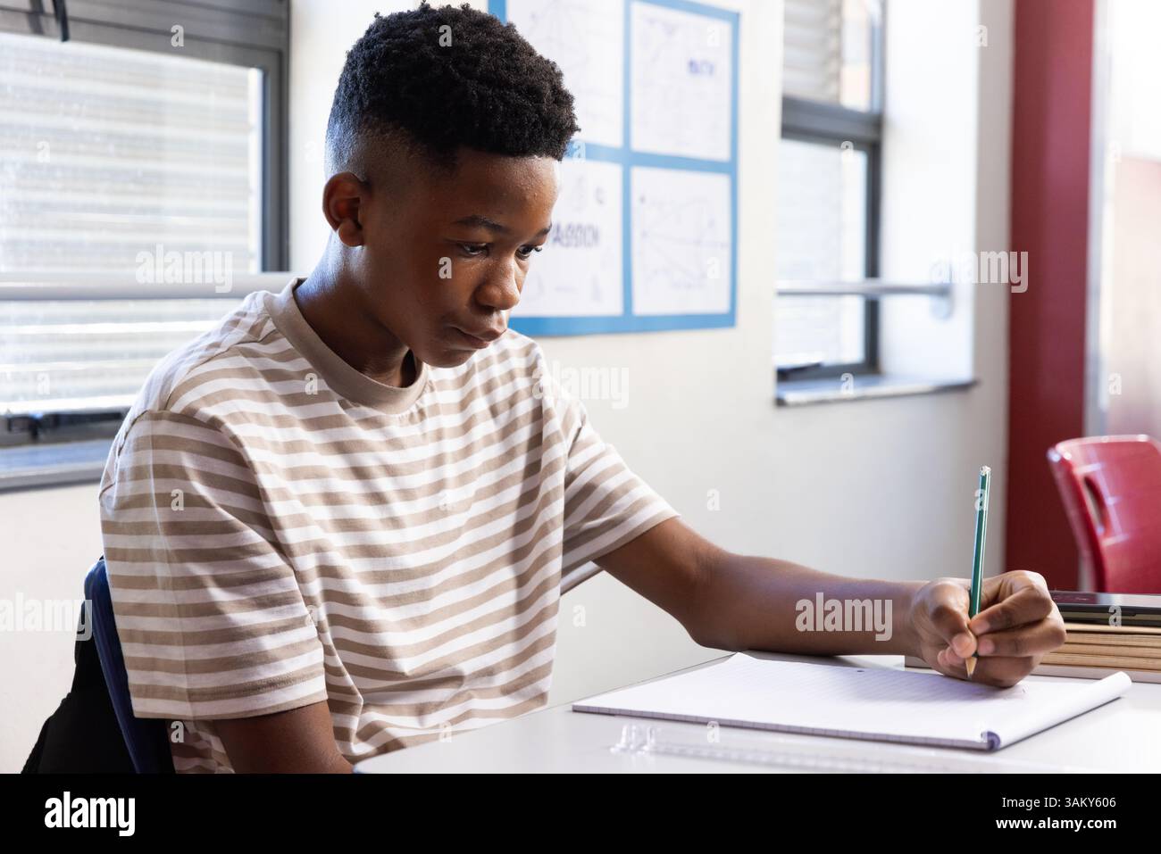 In school, boy writing in notebook at desk, concentrating on work Stock ...