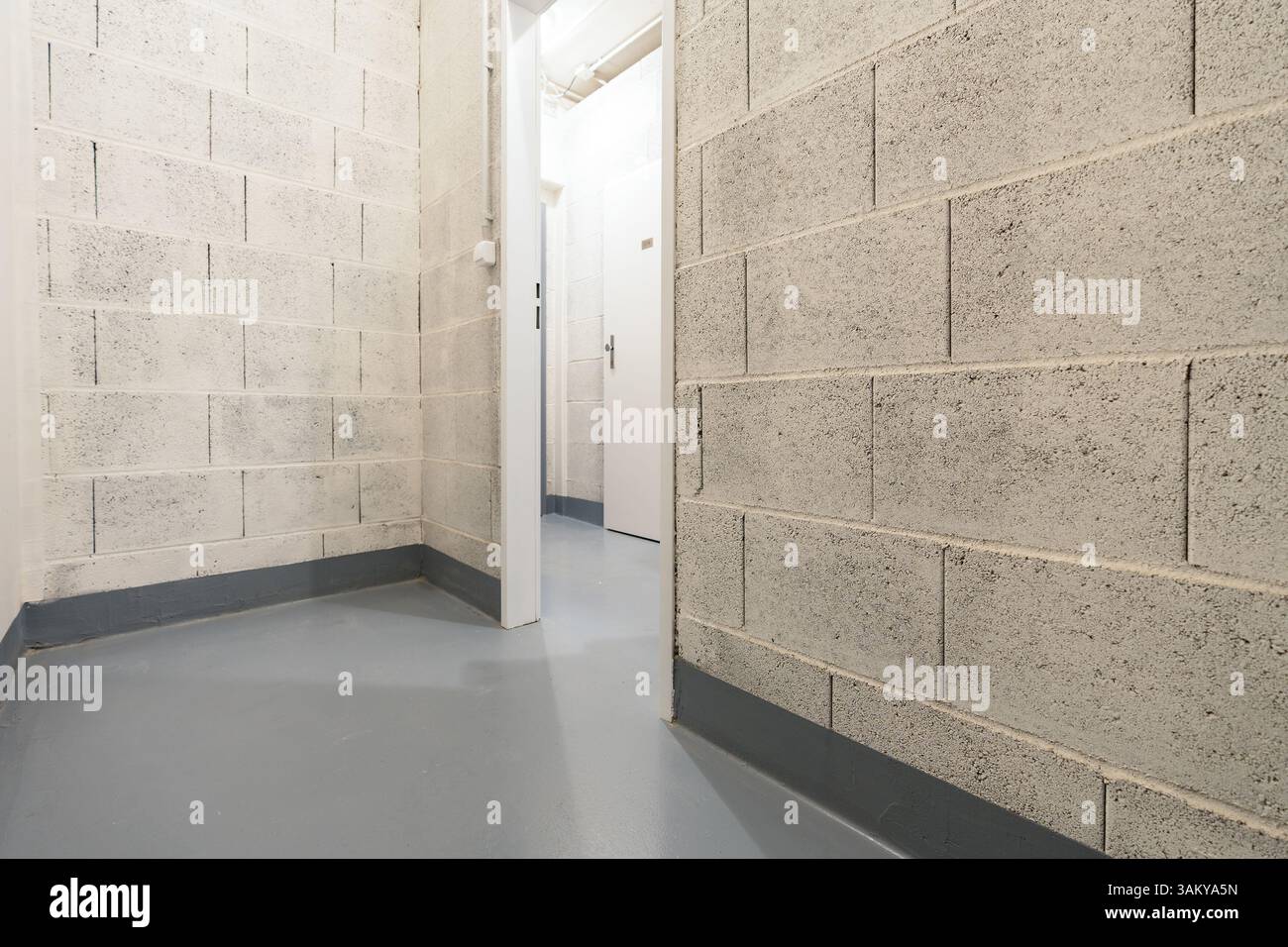 Small utility storage room with concrete walls and exit door in modern ...