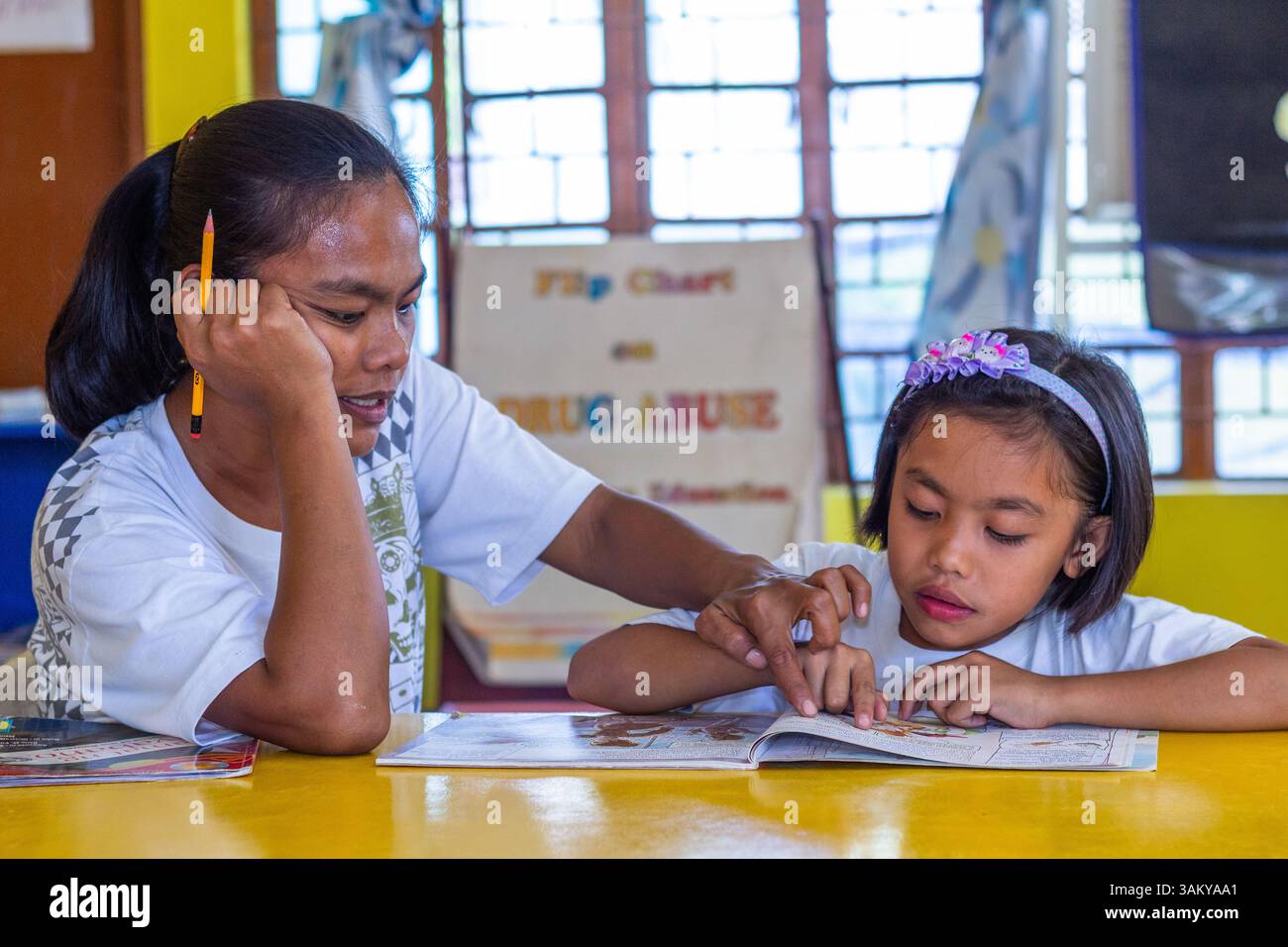 A Filipino mother reads with her daughter at a public elementary school ...