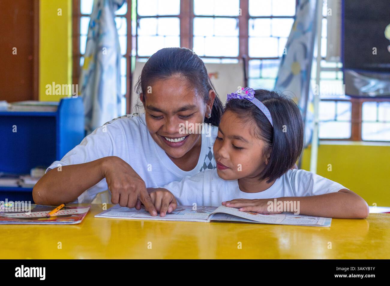 A Filipino mother reads with her daughter at a public elementary school ...
