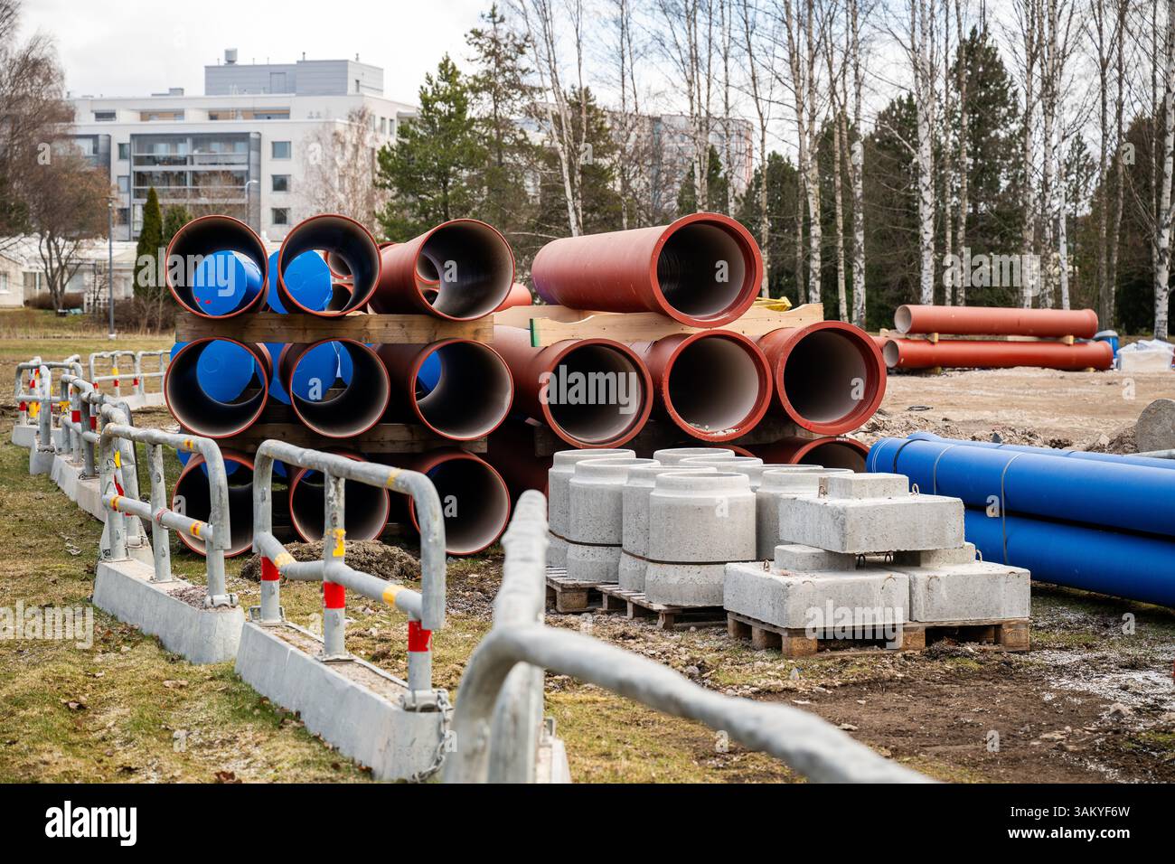 Red construction pipes stacked on wooden pallets at a construction site ...
