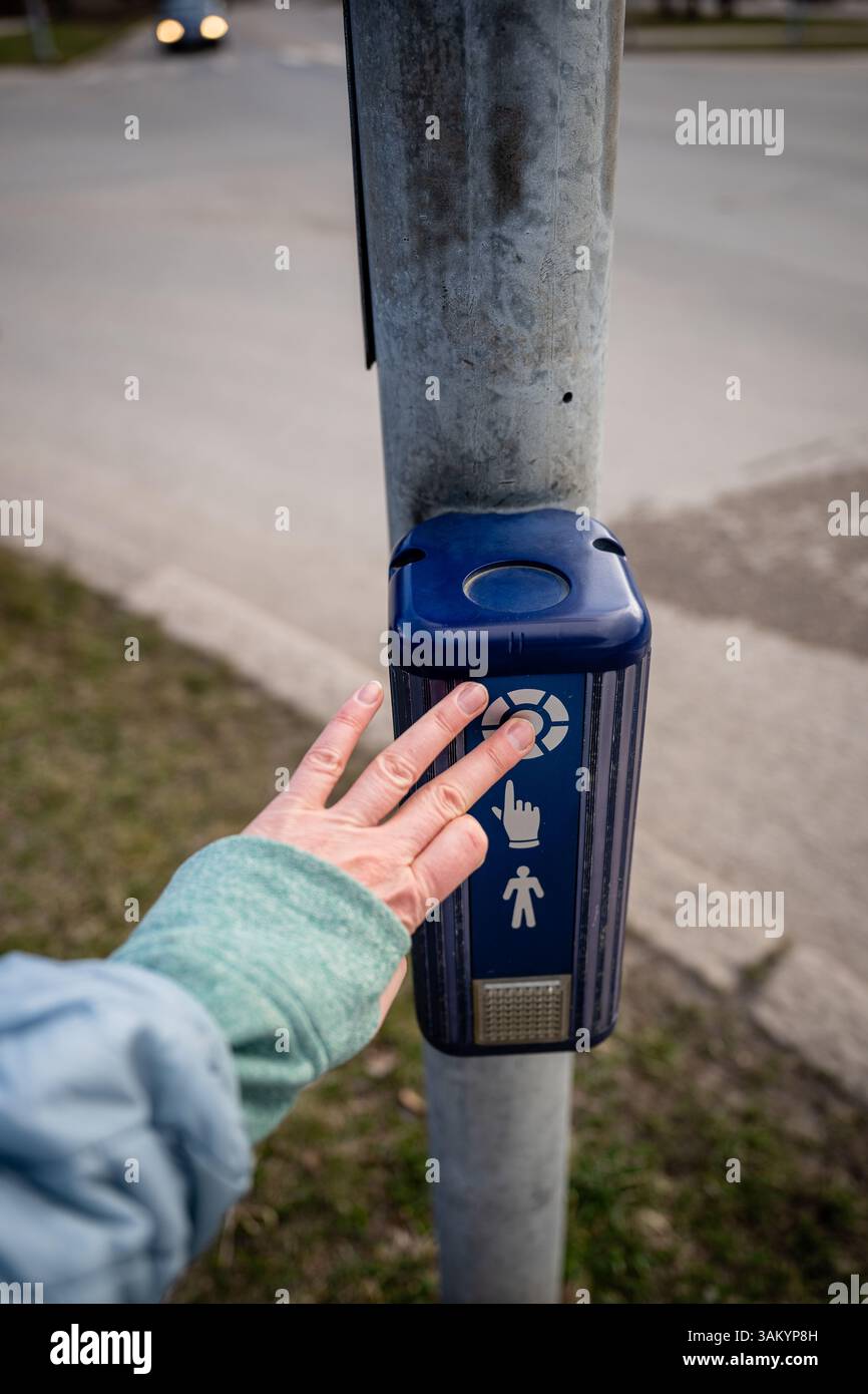 Human hand pressing crosswalk button on traffic light pole in urban ...