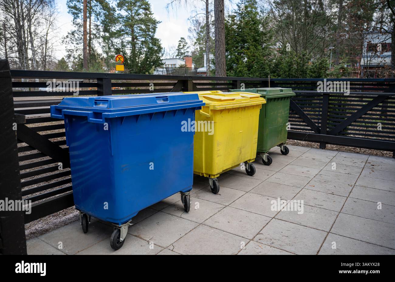 Three colored garbage bins for waste separation placed on outdoor ...