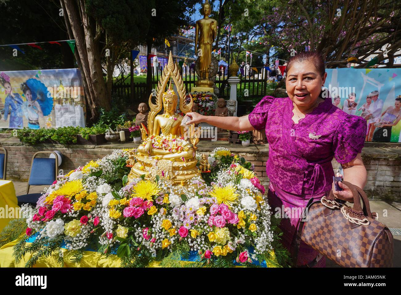 London UK 13 April 2025. A worshippers with a golden statue of Buddha ...