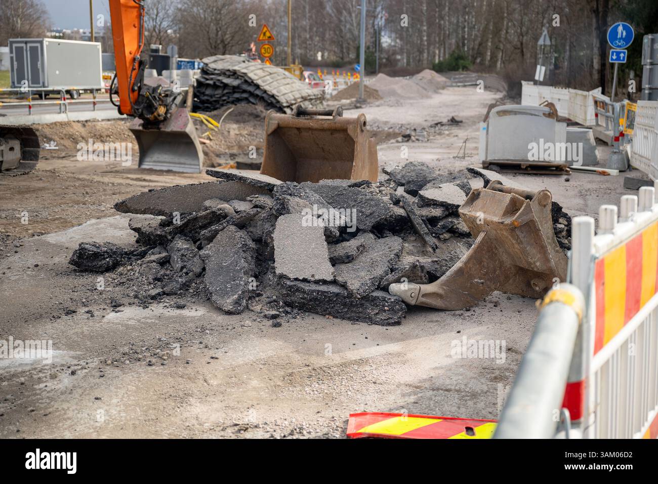 Broken asphalt pieces and excavator buckets at a road construction site ...