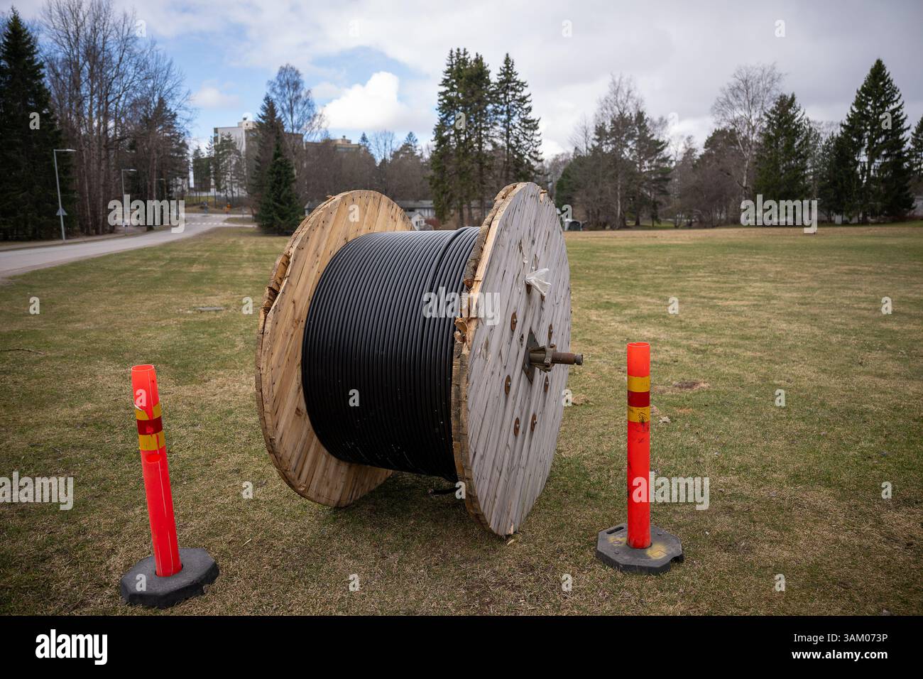 Large wooden cable spool with black conduit on grassy field near ...