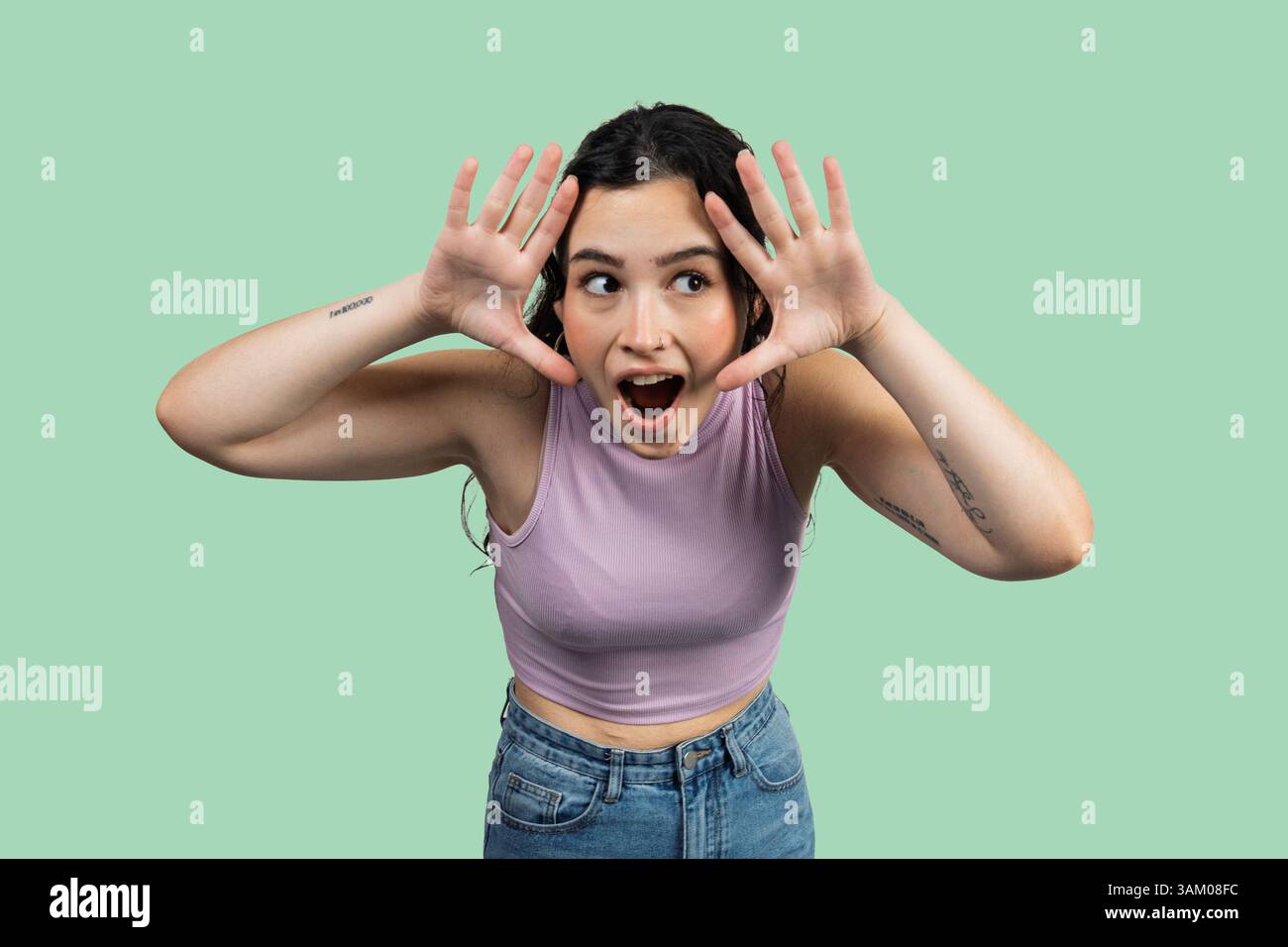 Young woman expressing surprise with raised hands and open mouth ...