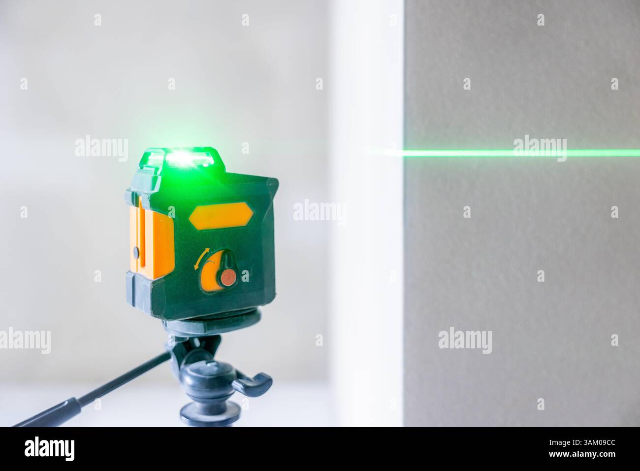 Cross line laser level tool projecting green beam on wall Stock Photo ...