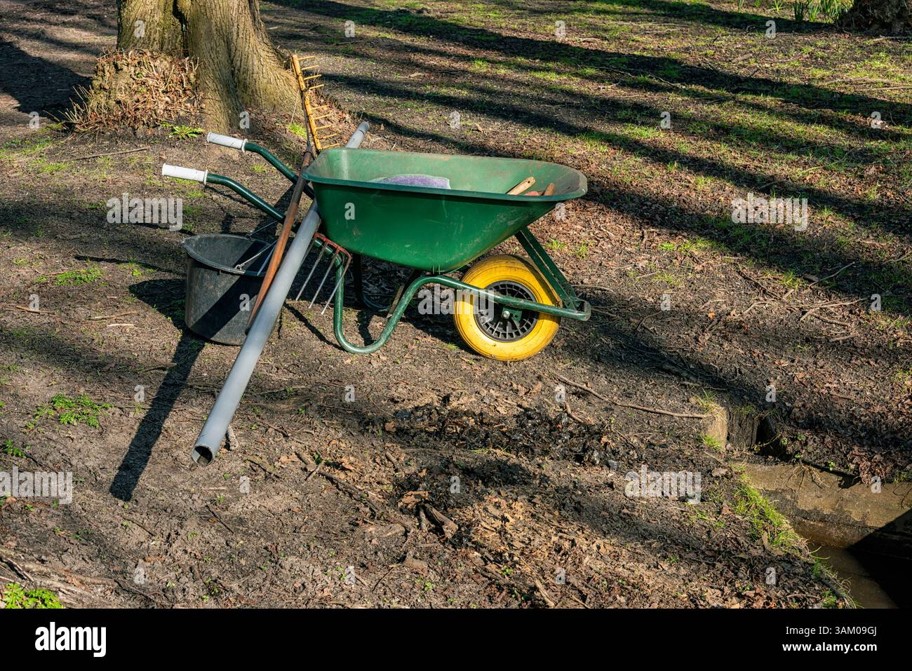 green wheelbarrow with yellow front tire stands outside in the forest ...