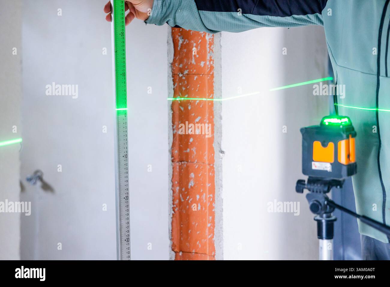 Construction worker using laser level and ruler taking measurements on ...