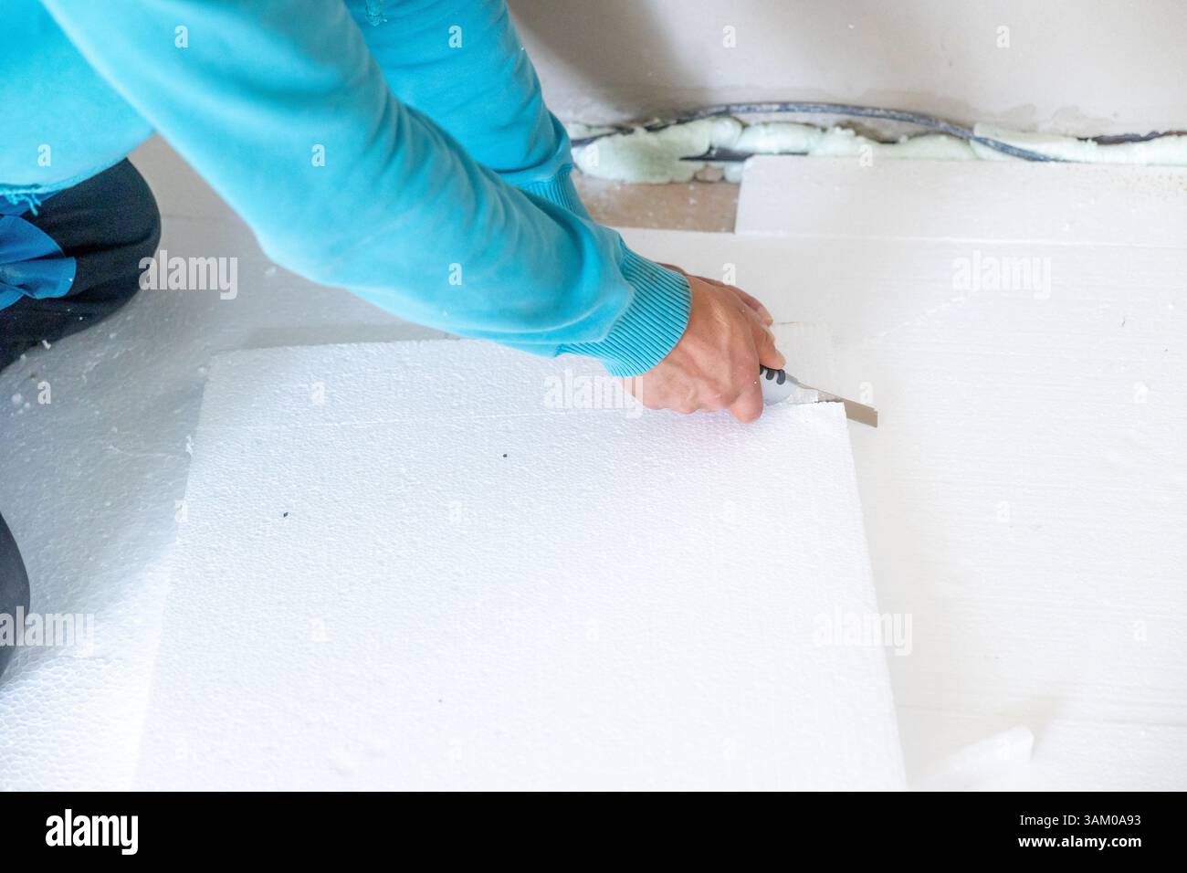 Construction worker cutting styrofoam insulation board with utility ...