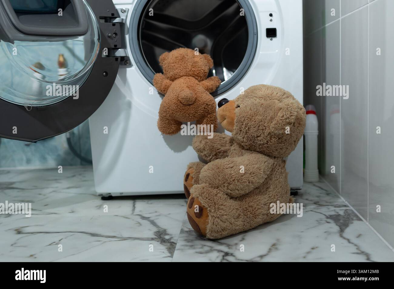Two adorable teddy bears are playfully interacting beside a washing ...