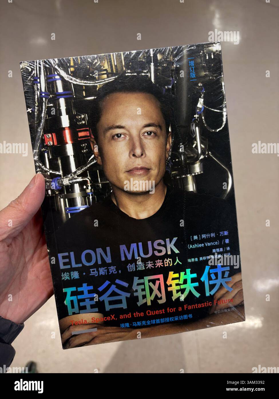 A hand holds Elon Musk biography book written in Chinese. The book is ...