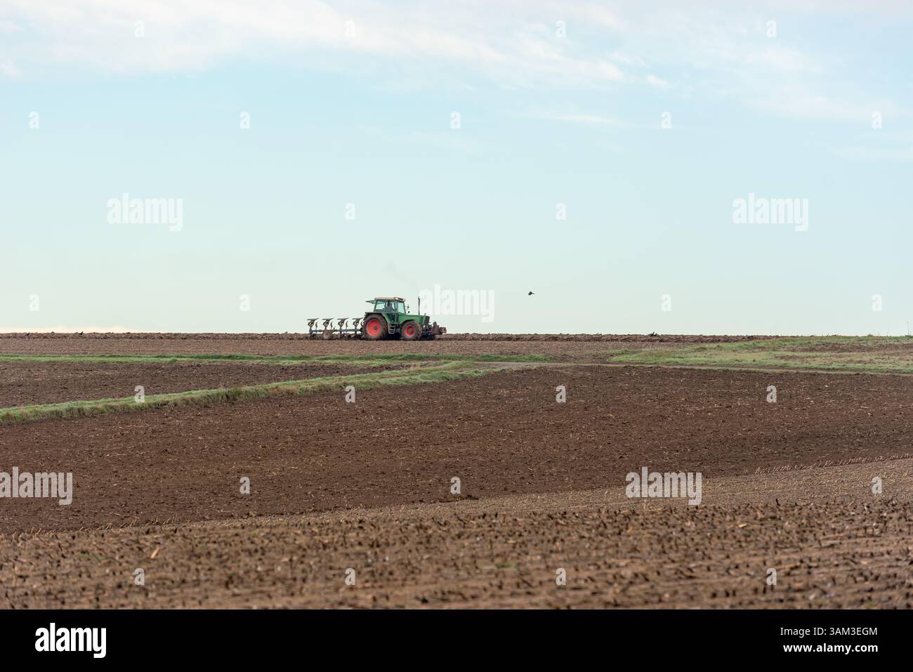 Side view with a single tractor working the agricultural fields in the ...