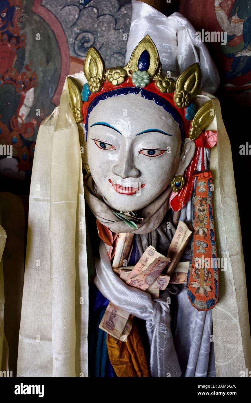 Devotional statue adorned with khatas and currency offerings inside ...