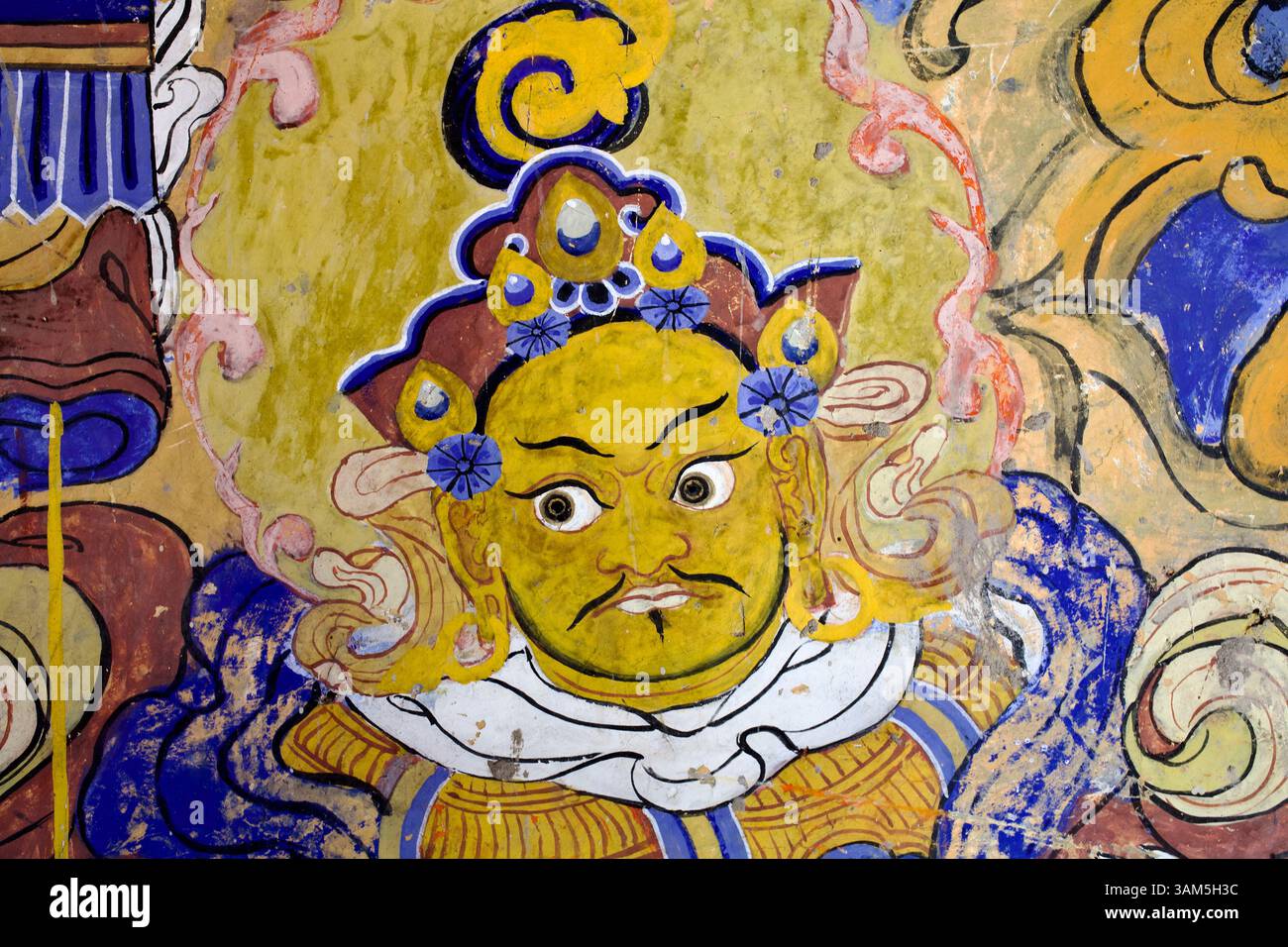 Close-up of wrathful deity with yellow face and floral crown in Thiksey ...