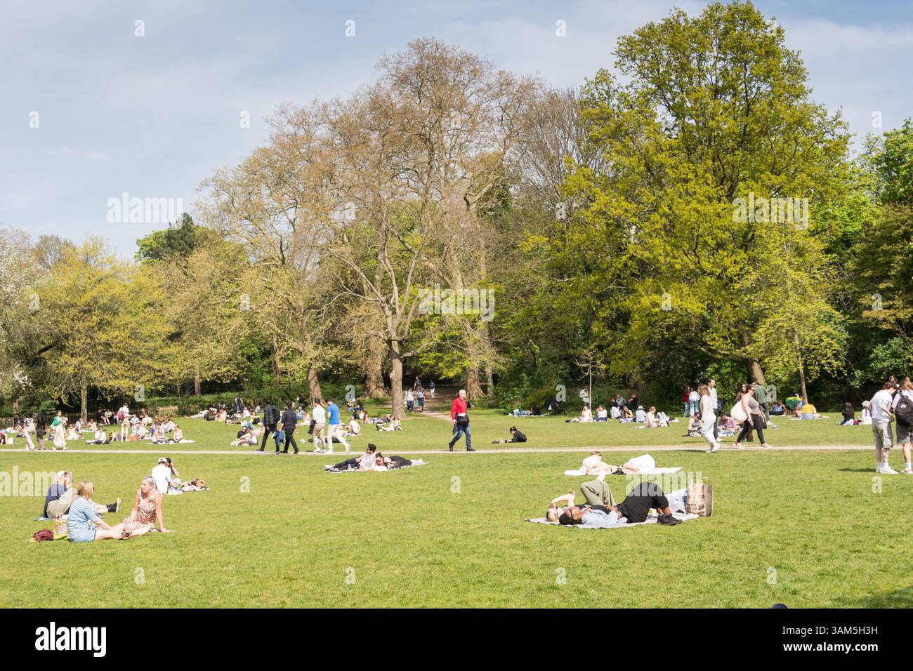 People sunbathing and relaxing in the Spring sun in Holland Park ...