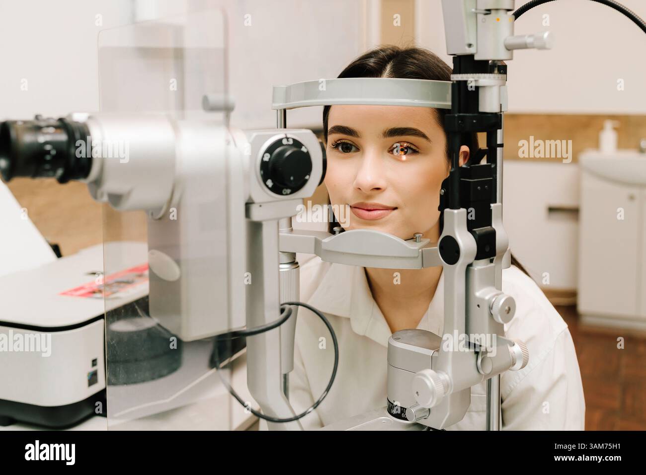 Ophthalmologist illuminates eye of patient with light from slit lamp to ...