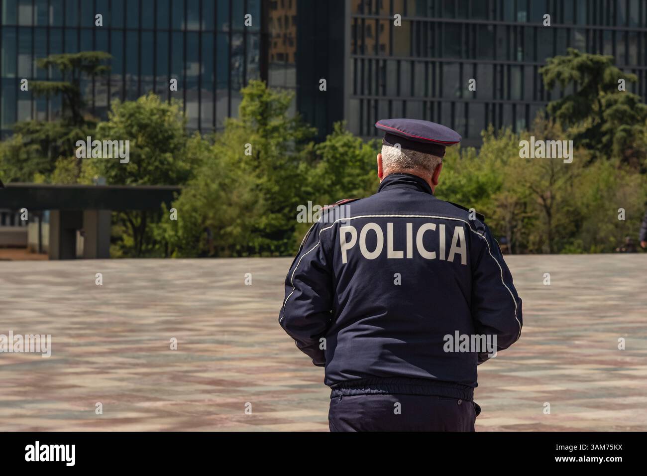 An old man wearing police uniform walking on the street of Europe. Back ...