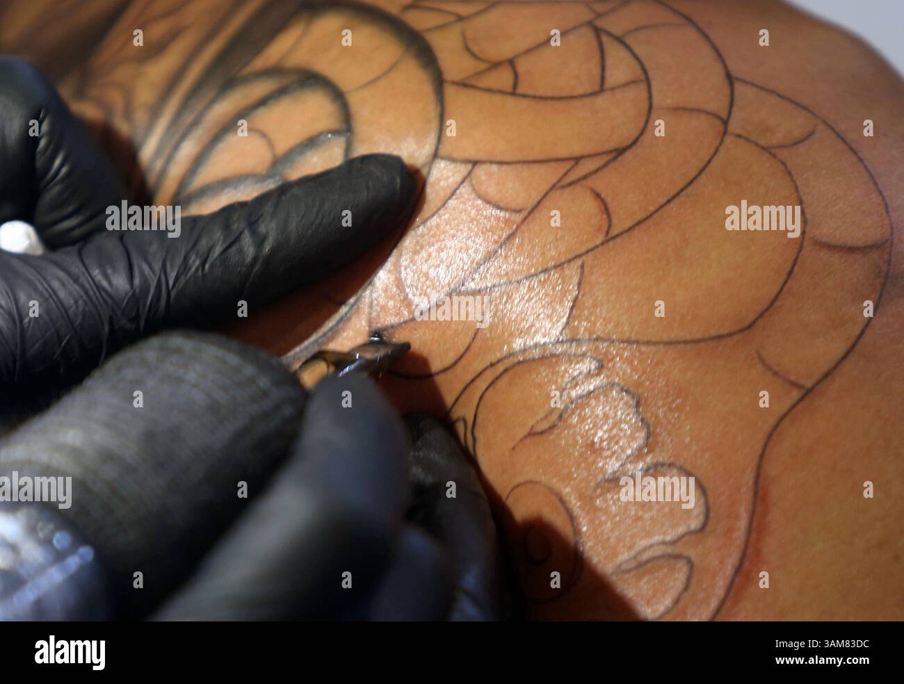 April 13, 2025: A tattoo artist inks a customer during the 12th ...