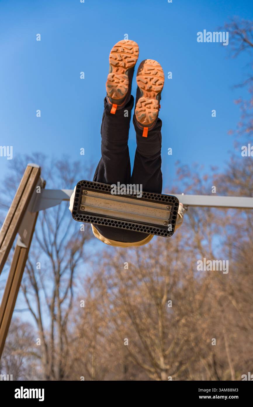 Child swinging upside down on swing seat in park, view from below, sunny winter day Stock Photo ...