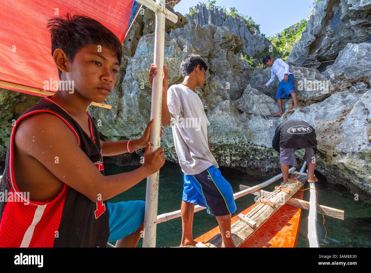 Filipino tour guide and banca boat crew docking at the rocky outcrop ...