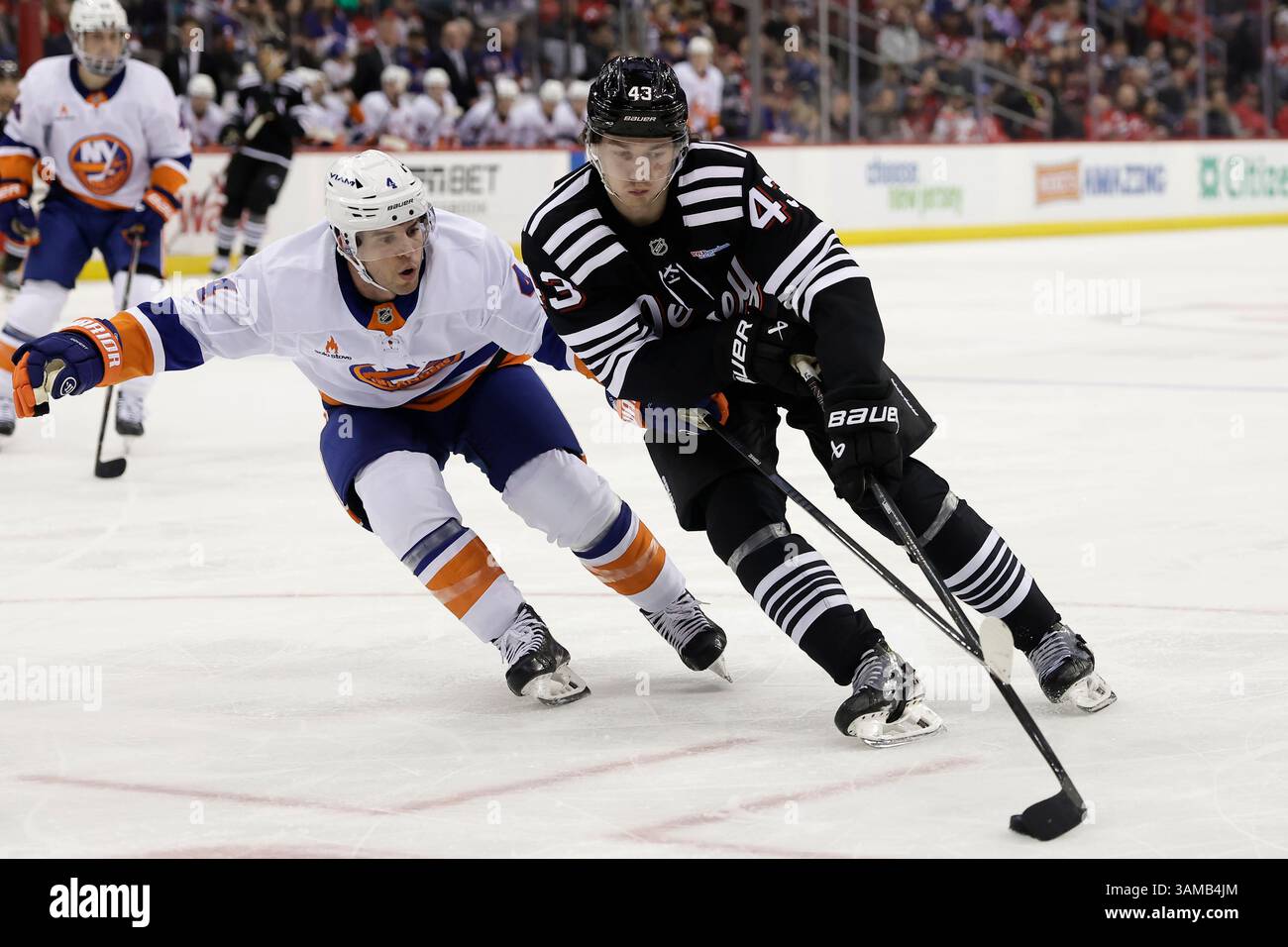 New Jersey Devils defenseman Luke Hughes (43) controls the puck past New York Islanders ...