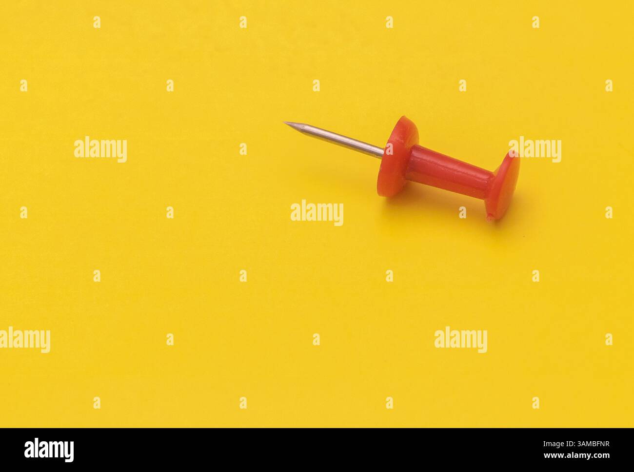 A red pushpin on a yellow background, a close-up shot with soft ...