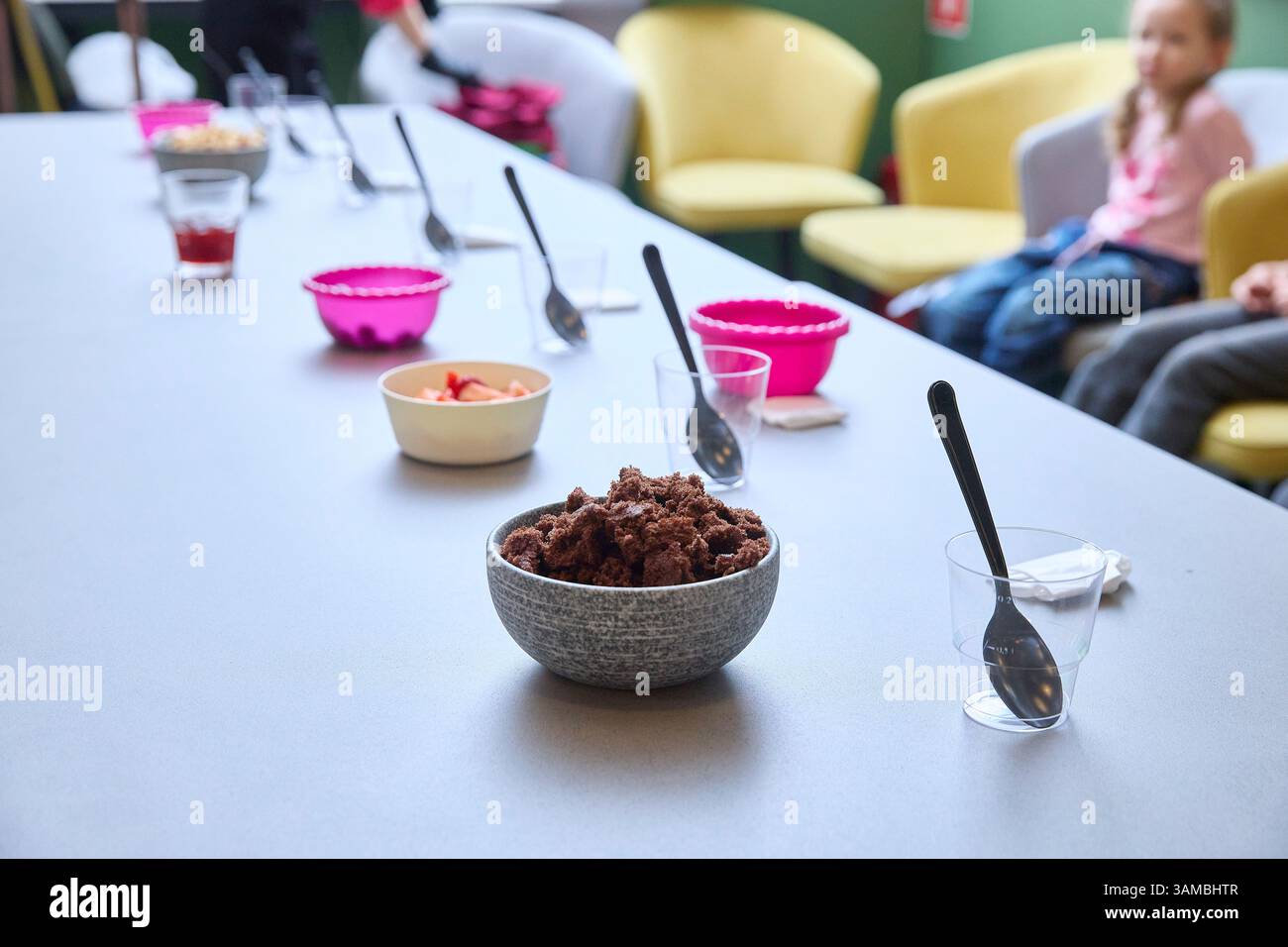Those gathered at a long table are teaching children how to cook trifle ...