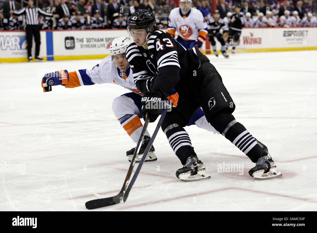 New Jersey Devils defenseman Luke Hughes (43) controls the puck past New York Islanders ...