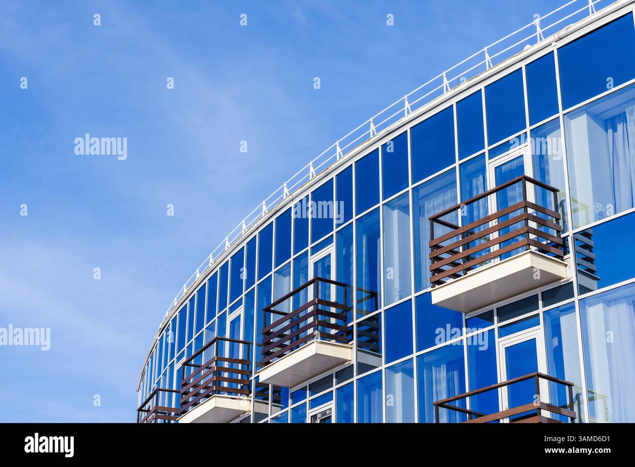 Blue glass building featuring wooden balconies, reflecting the sky. A ...