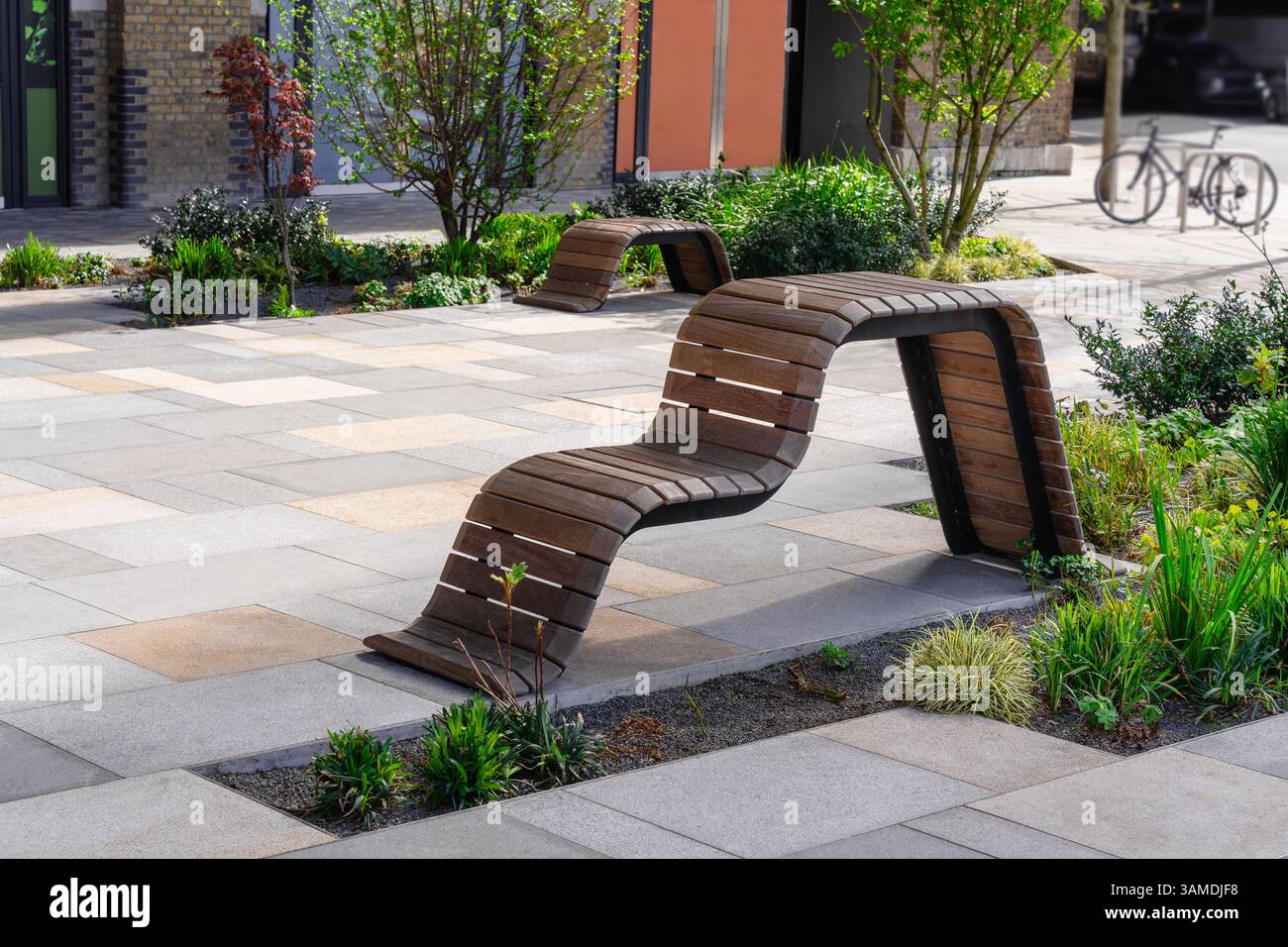 Curved wooden bench with modern wave design stands on tiled public ...
