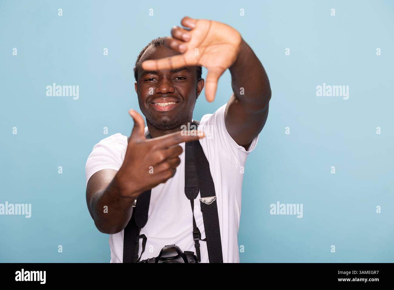 African American man standing and making a frame hand gesture towards camera. Smiling male ...