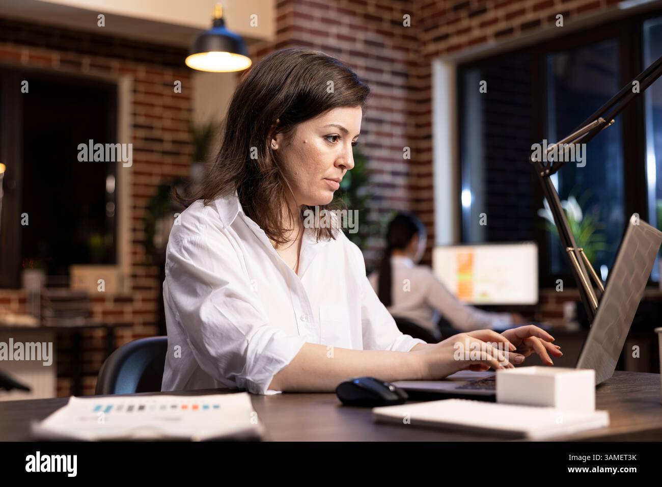 Focused businesswoman works into the night, checking emails and ...
