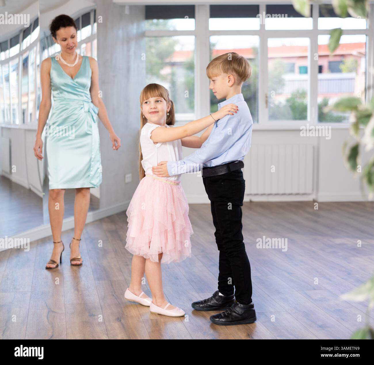 Tween girl and boy practicing waltz in dance hall with female mentor ...