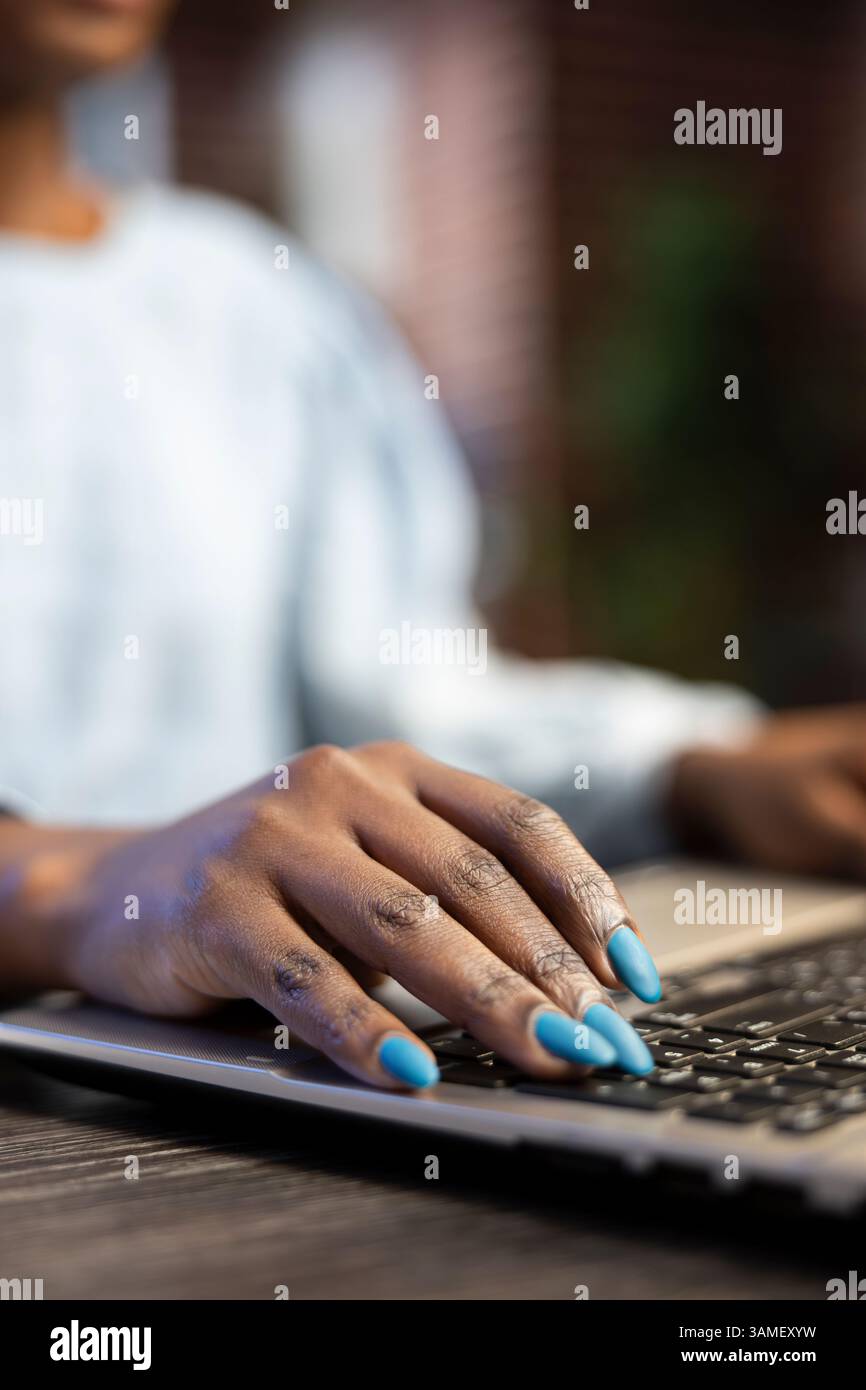 Closeup of black female individual typing on laptop, her fingers ...