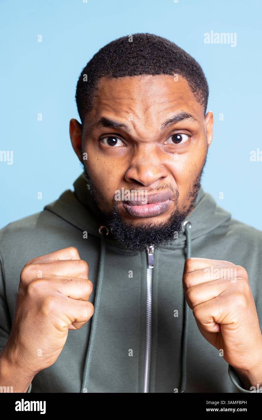 Confident powerful young man preparing to fight and box with his fists ...