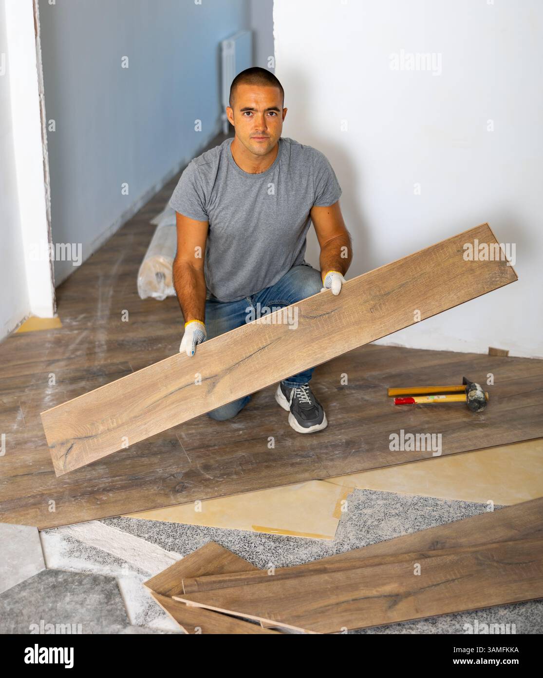 Male worker installing new wooden laminate flooring. The combination of ...