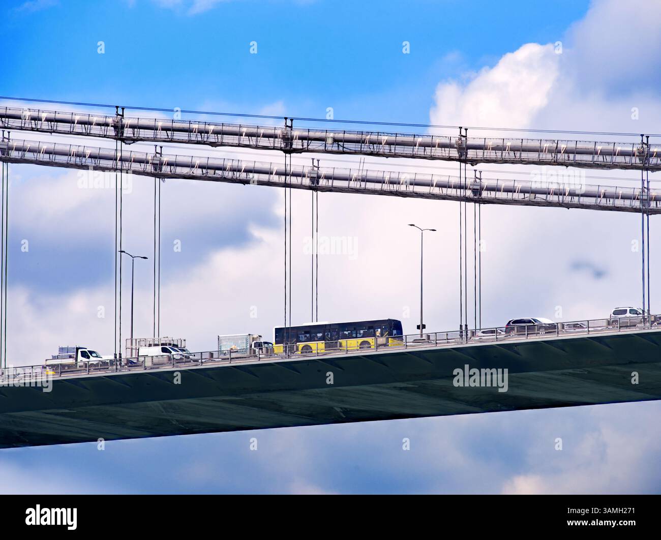 Vehicles crossing a bridge with overhead gantries against a blue sky ...