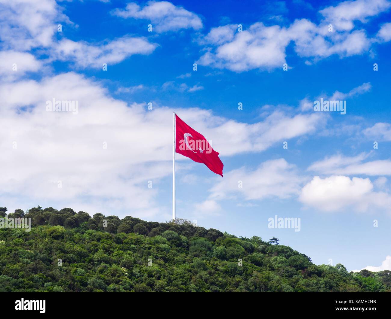 Red Turkish flag with white crescent and star flying on tall pole above ...