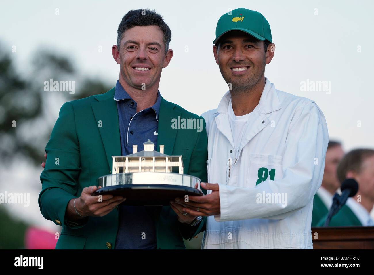 Rory McIlroy, of Northern Ireland, holds the trophy with caddie Harry ...