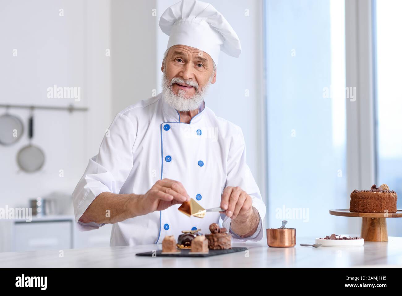 Elderly pastry chef decorating tasty desserts with edible gold leaf ...