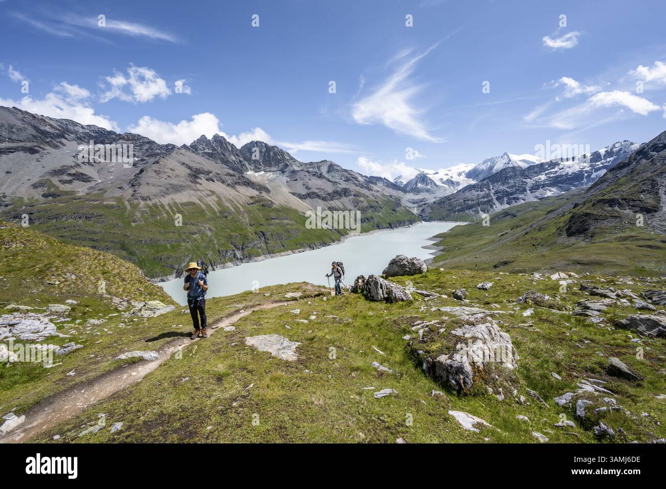 Two mountaineers on a hiking trail at a blue mountain lake, reservoir ...