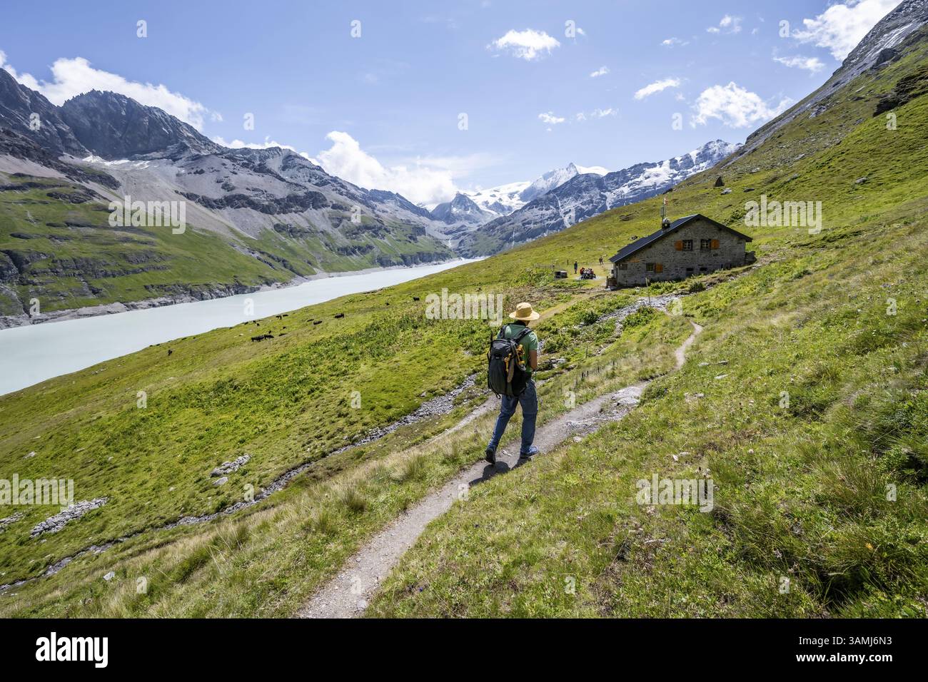 Mountaineer on a hiking trail in front of an alpine hut at a blue ...