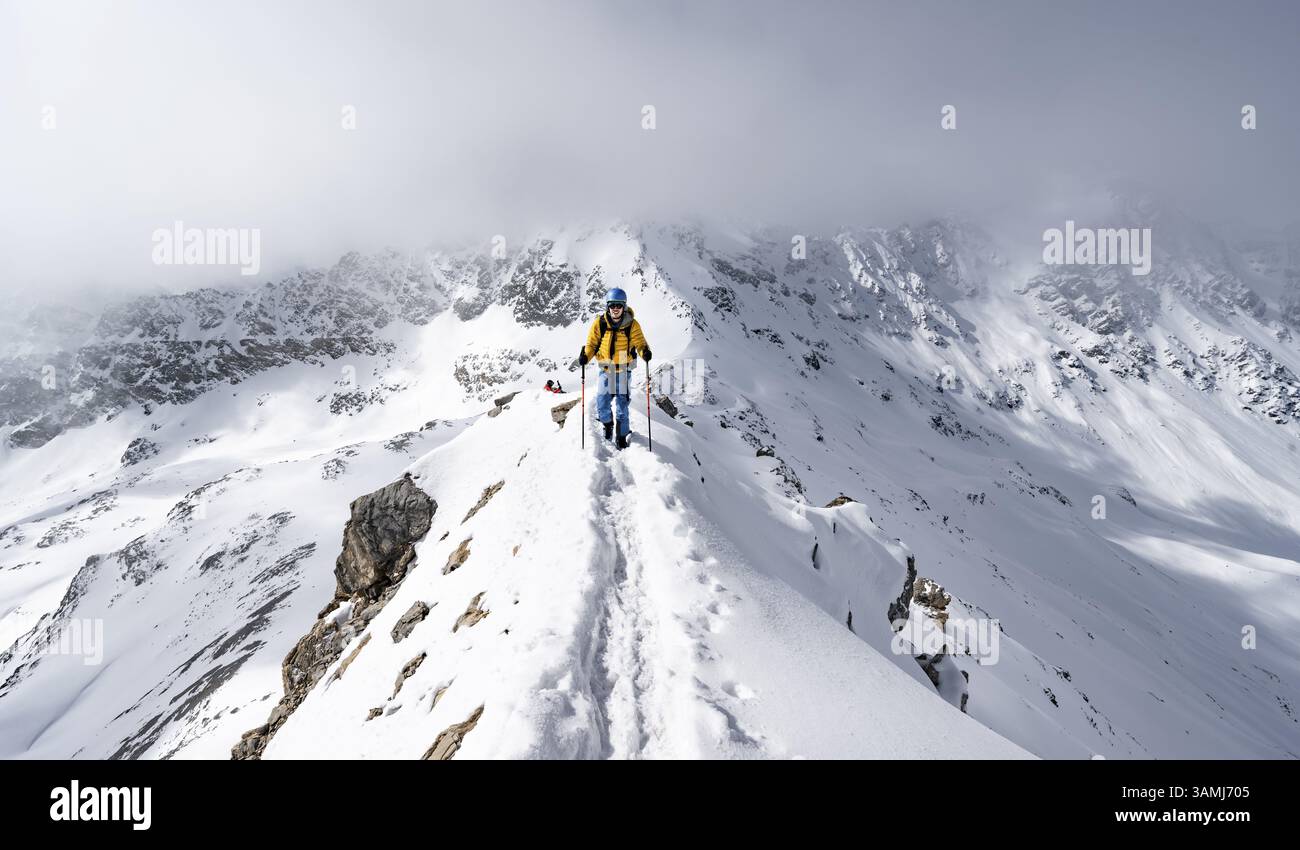 Mountaineer climbing up the narrow ridge of Piz Laviner, view of wintry ...