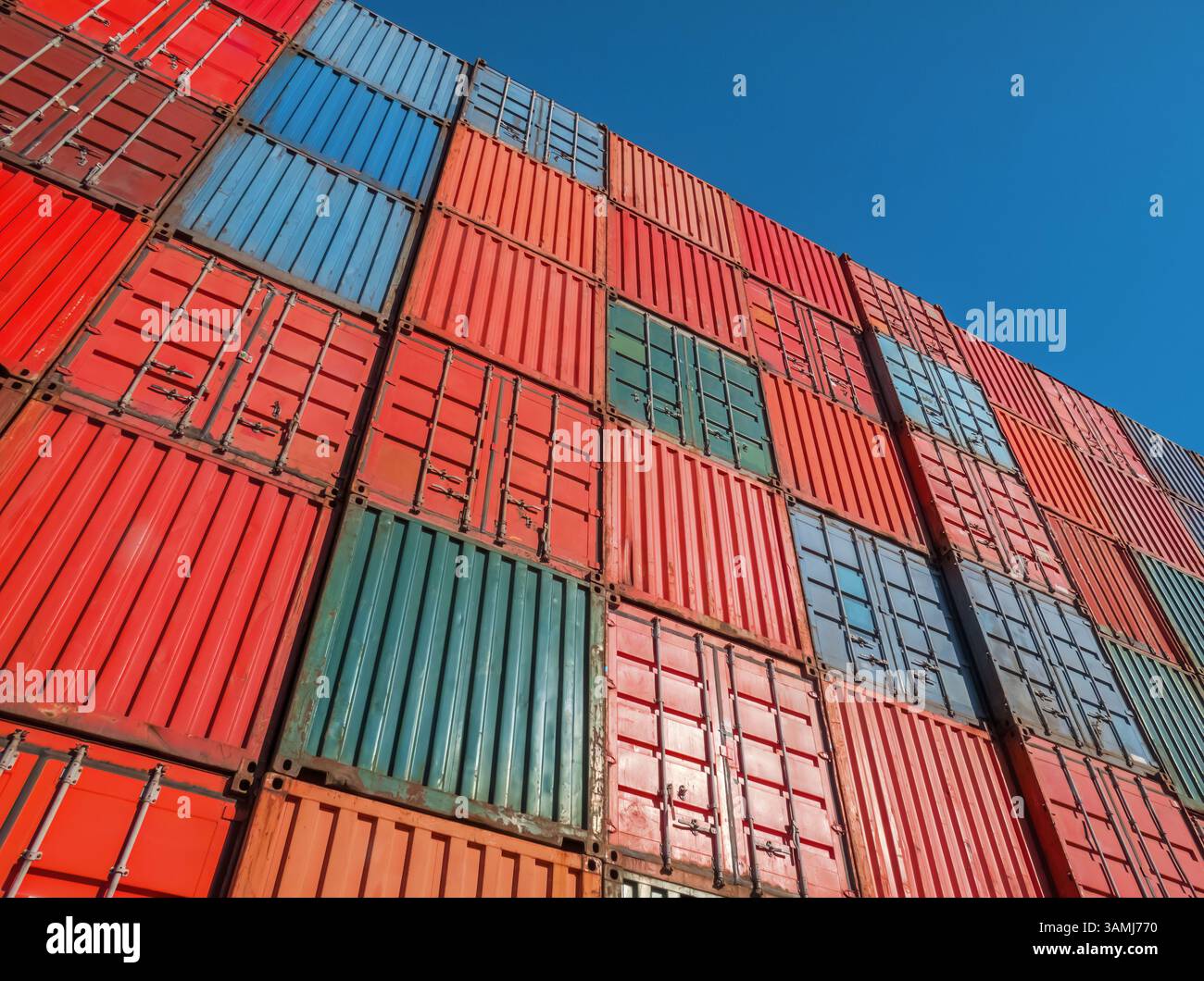 Worm’s eye view of a tall wall of freight containers against a clear ...